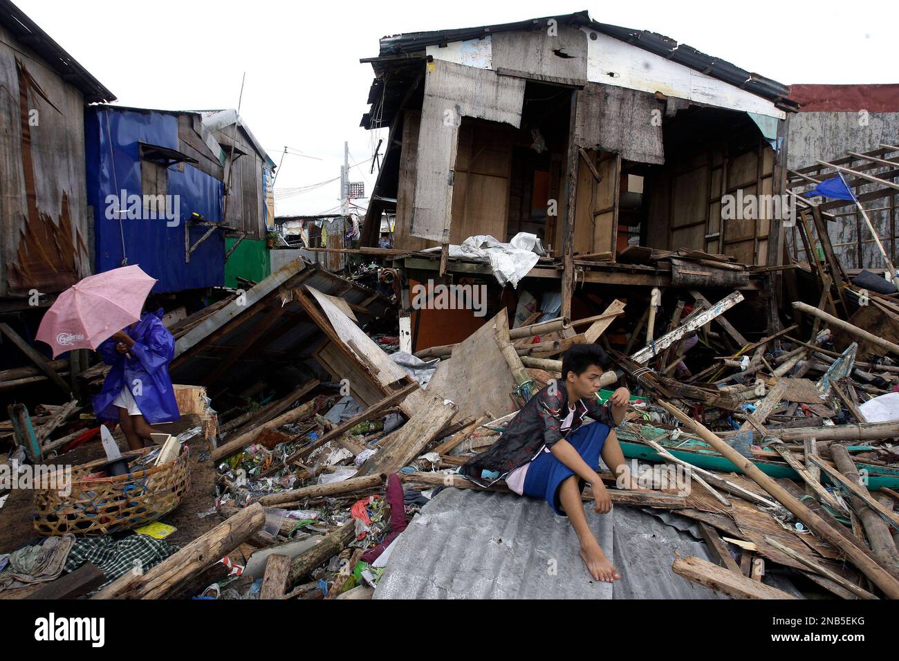 A man sits outside a damaged house after powerful Typhoon Nesat wiped ...