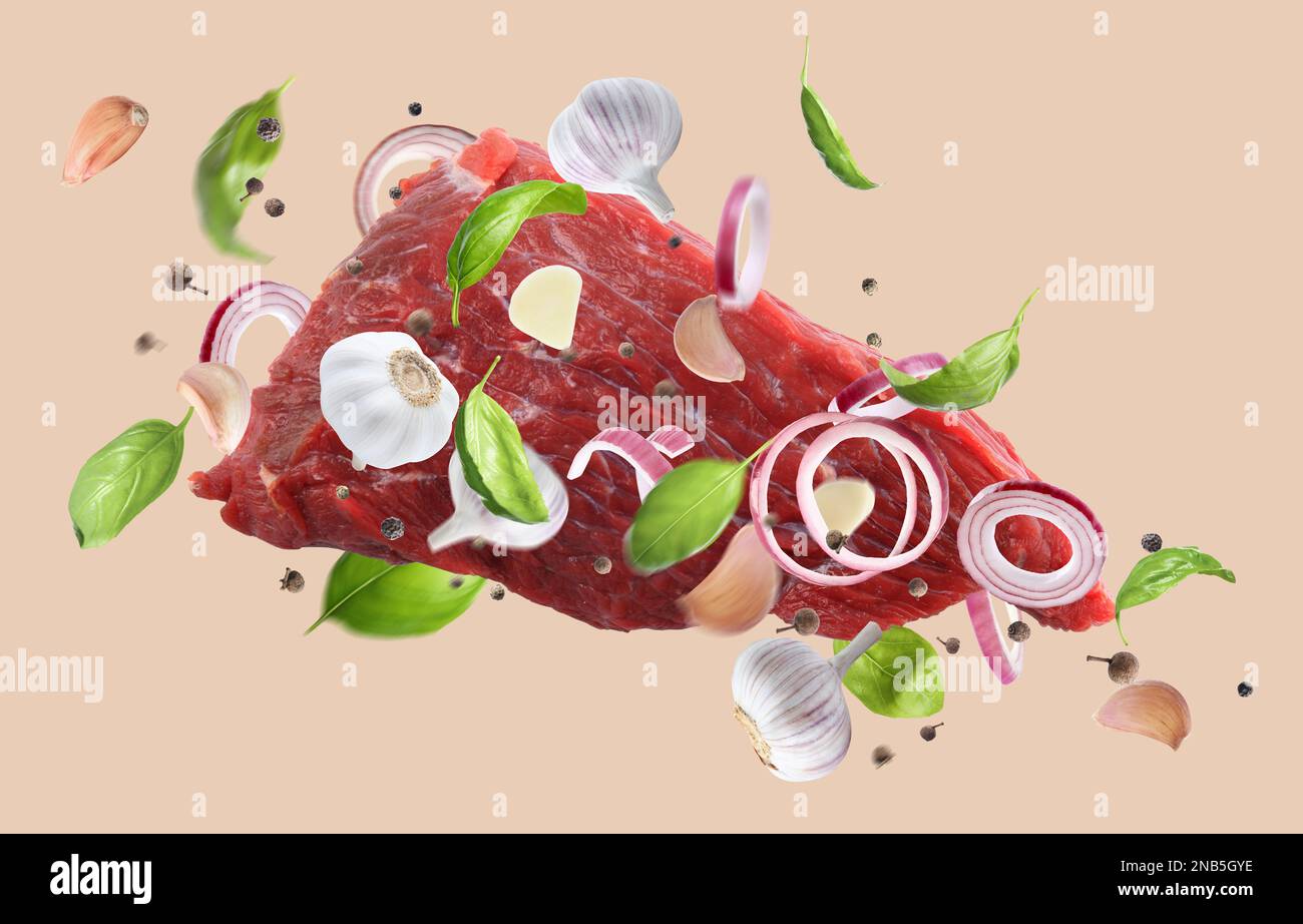 Fresh raw meat and different spices flying on beige background Stock ...