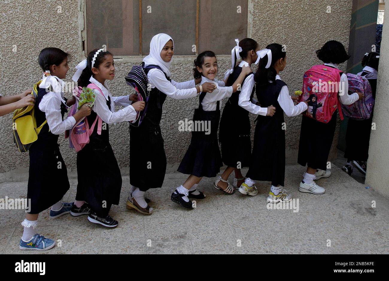Iraqi students queue to enter a classroom at a primary school during ...