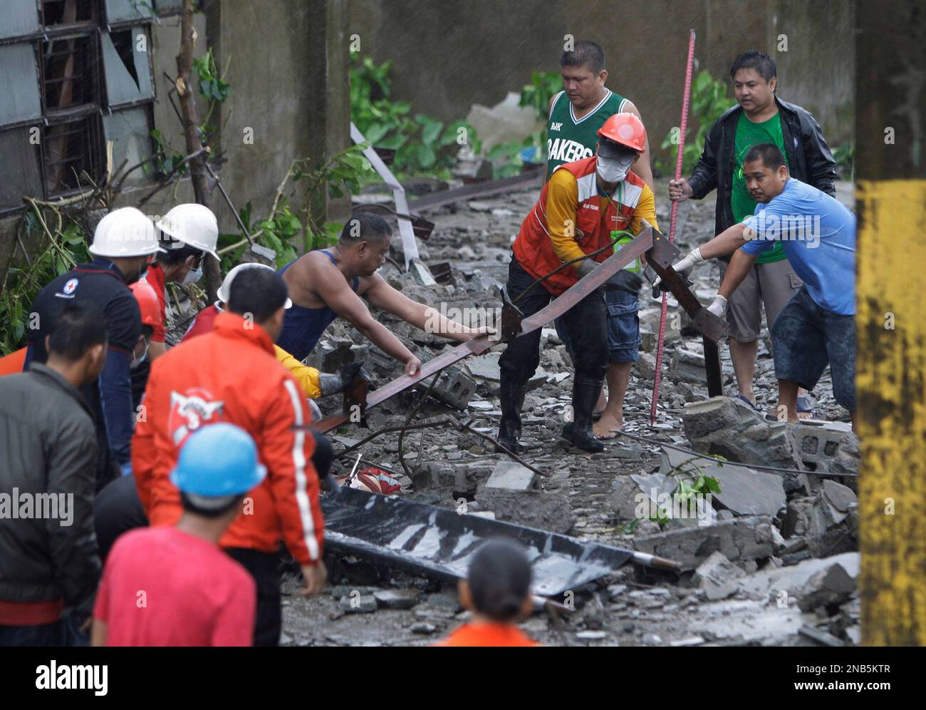 Rescuers remove a piece of metal as they try to recover the bodies of ...