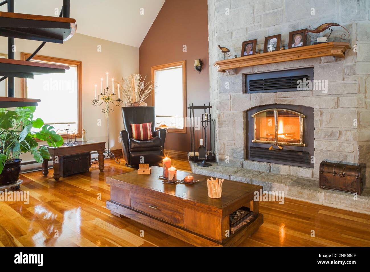Grey cut stone lit fireplace in living room with brown leather ...