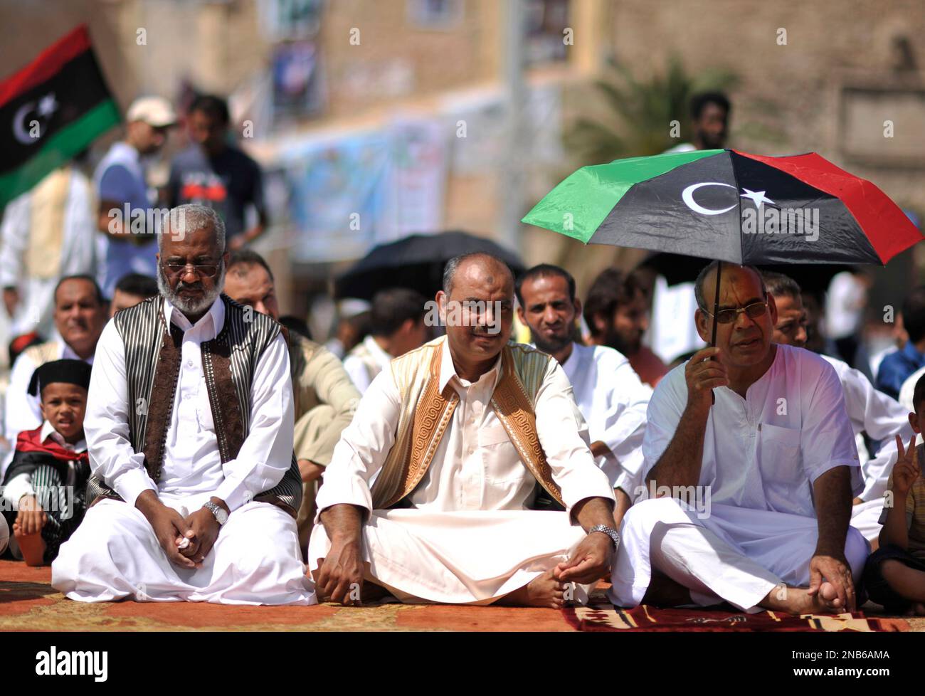 Libyans attend an open-air Friday pray while presenting the new flag of ...