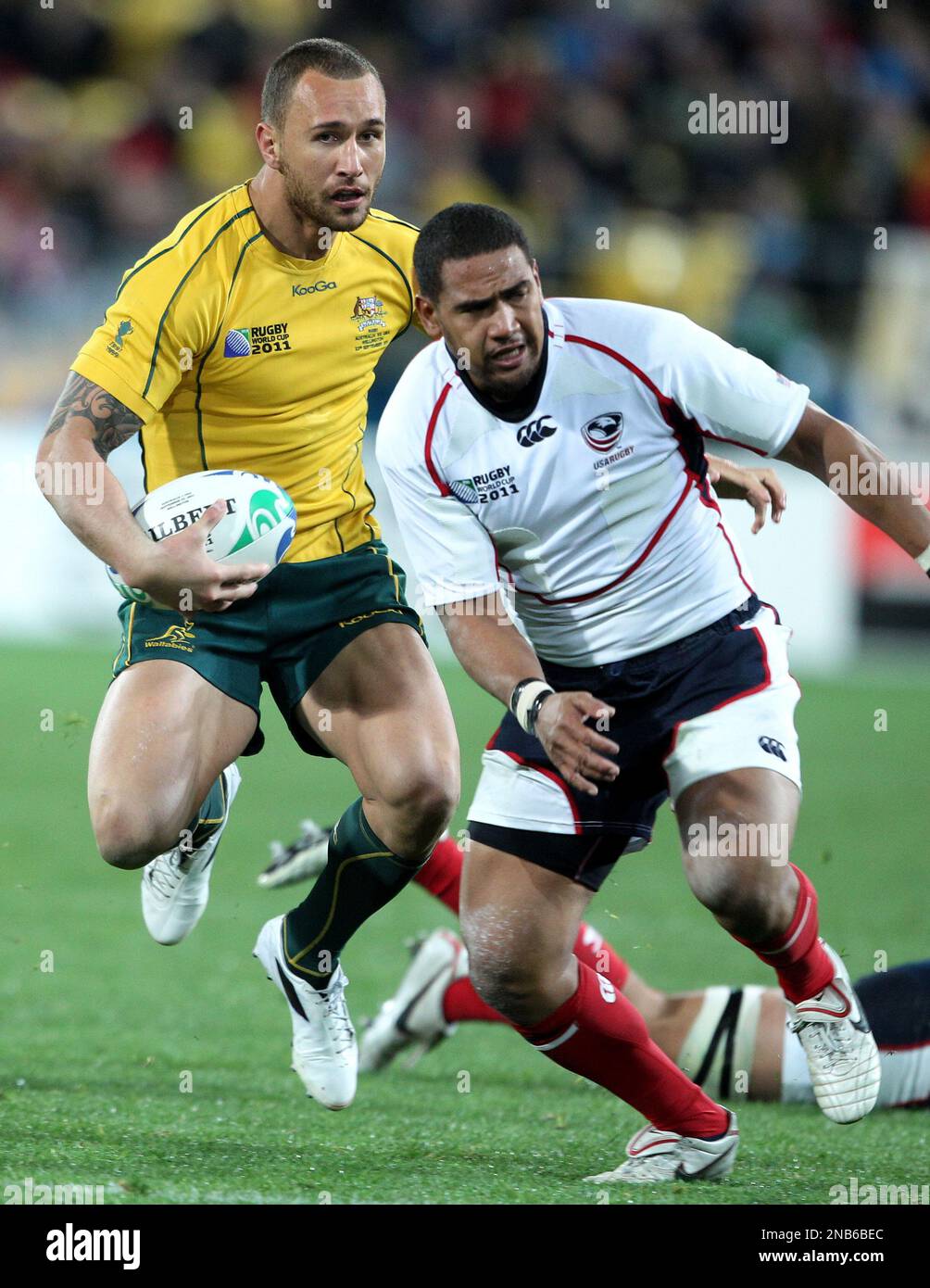 Australia's Quade Cooper, left, looks to run around Junior Sifa of the ...