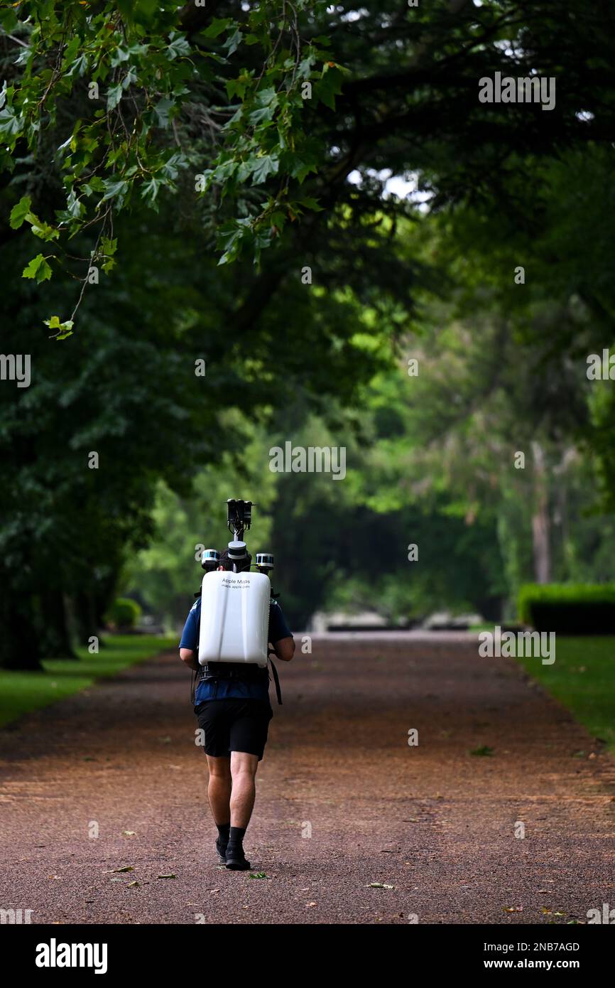 A man carries Apple Maps mapping equipment while walking through a park ...