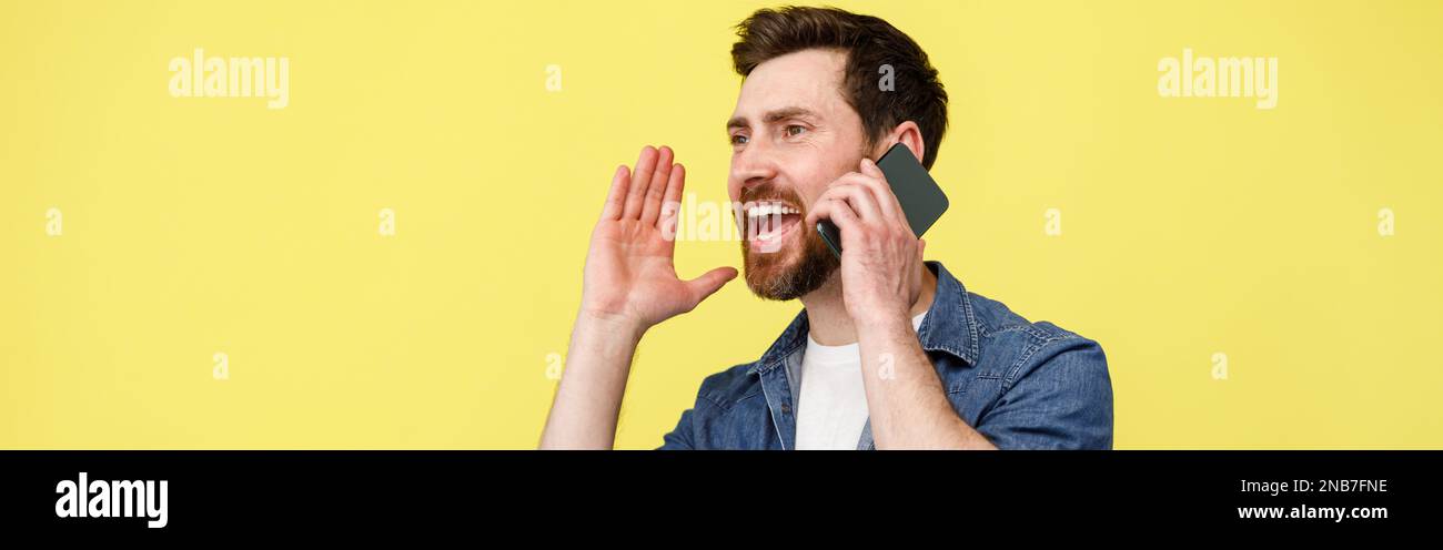 Happy man shouting loudly while talking on the phone and gesturing with ...