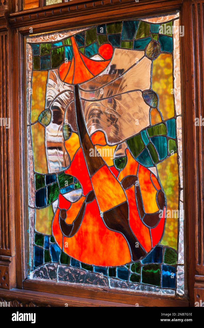 Close-up of stained glass window in old door with carved details in ...