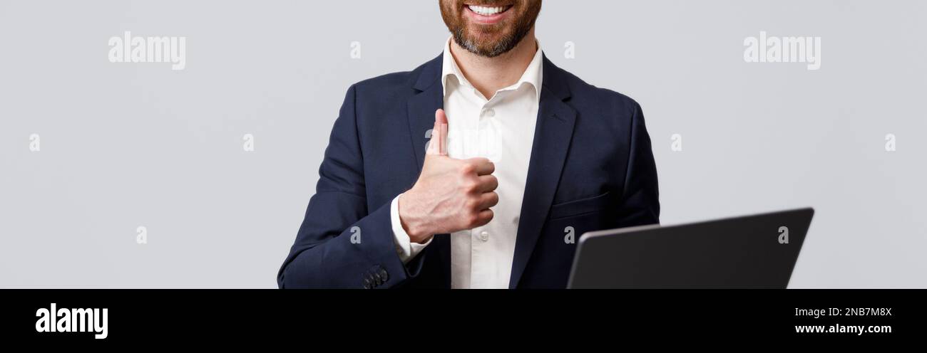 Satisfied male business coach in suit holding laptop showing thumb up ...