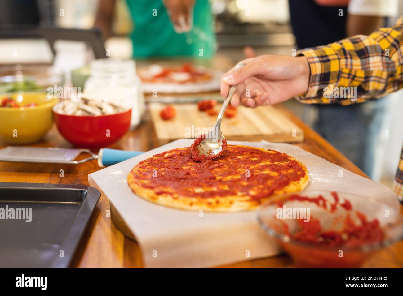 Hands of biracial teenage boy preparing pizza in kitchen. Hanging out ...