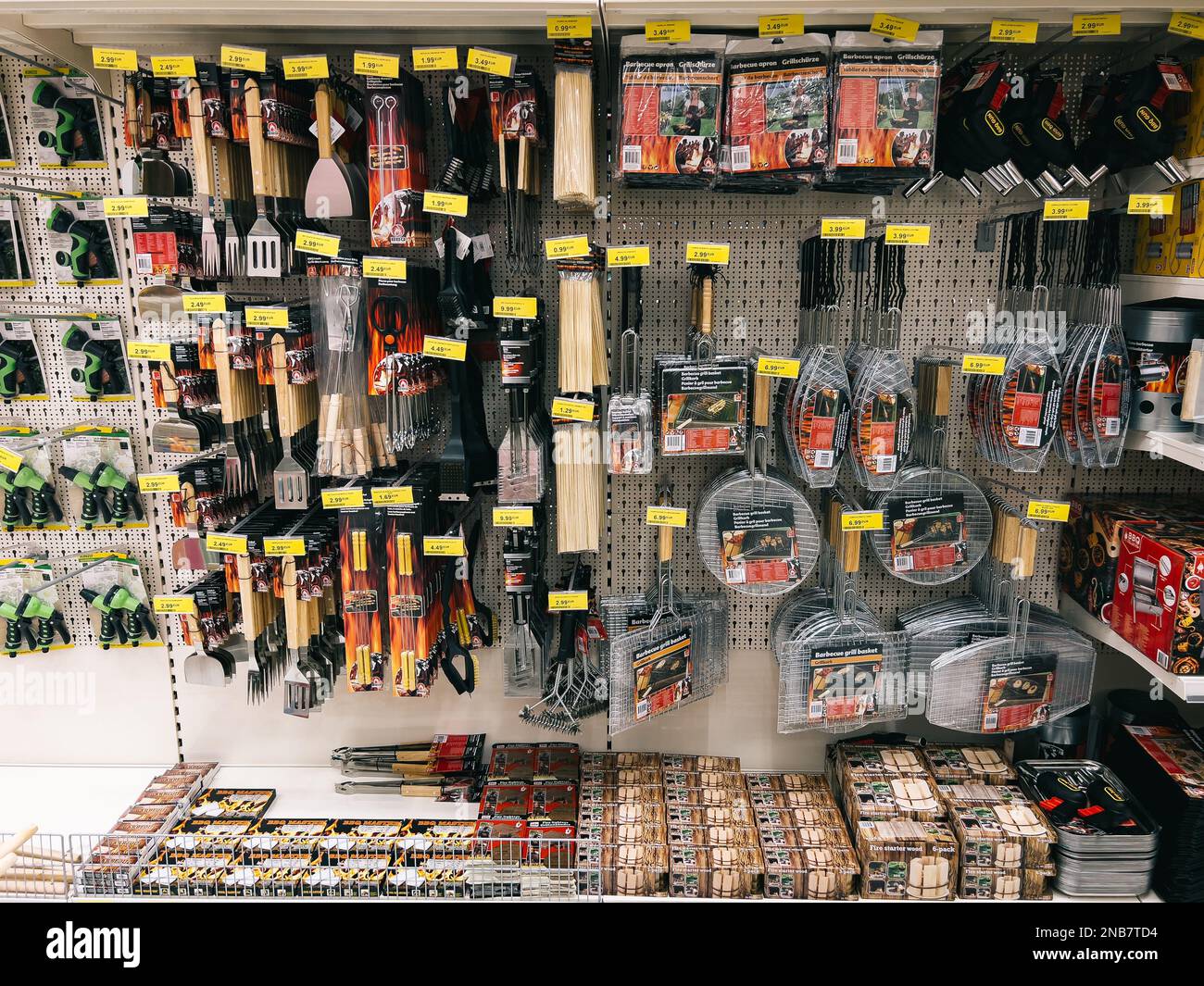 Turning paddles, large forks and grill grates hang on shelves in a ...