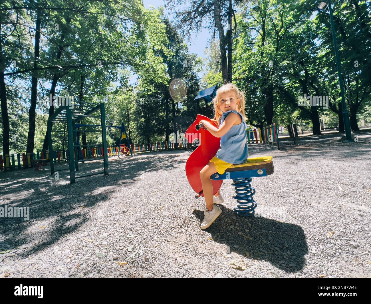Little girl sitting on a swing-spring in the playground Stock Photo - Alamy