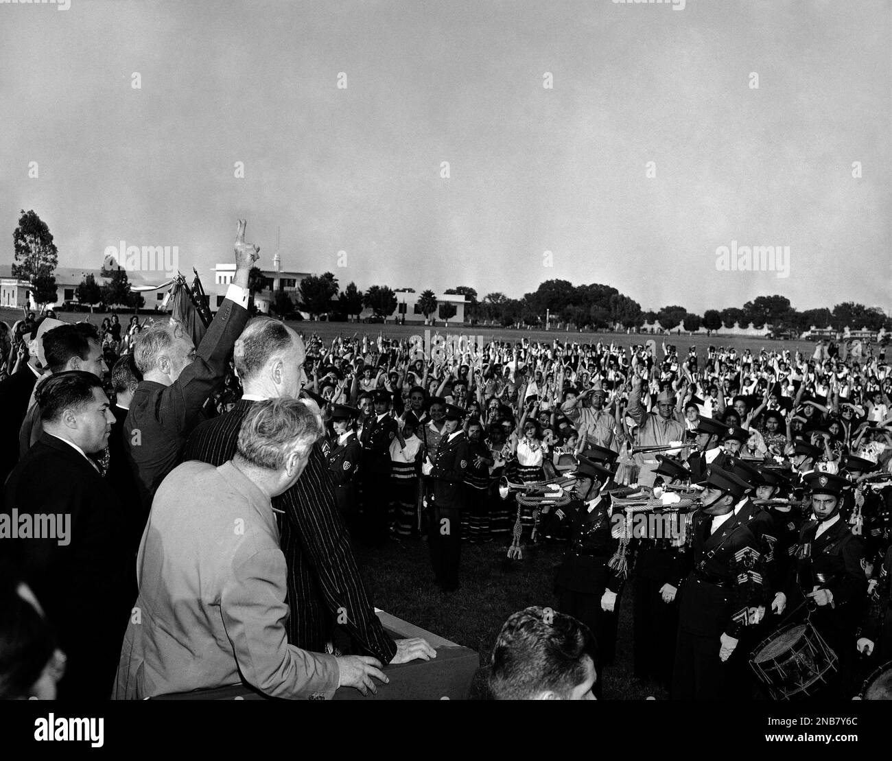 Cheering schoolchildren, their hands upraised with a “V” for victory ...