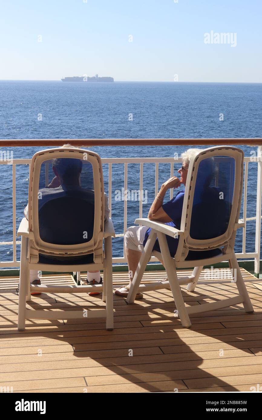 Senior cruise guests soak up the sun’s rays on the Promenade deck of ...