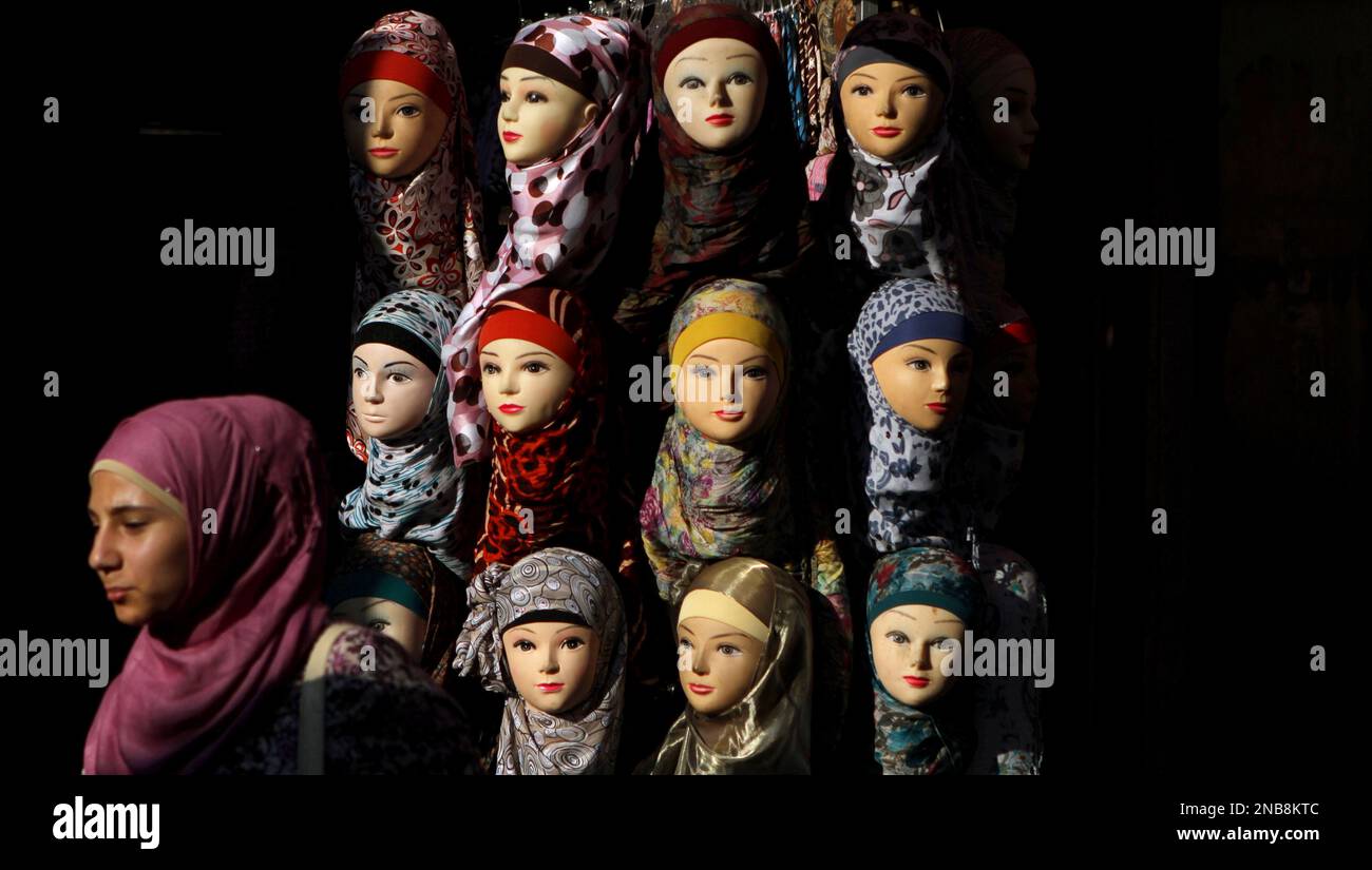 A woman walks past mannequins displaying Islamic head scarves for sale ...