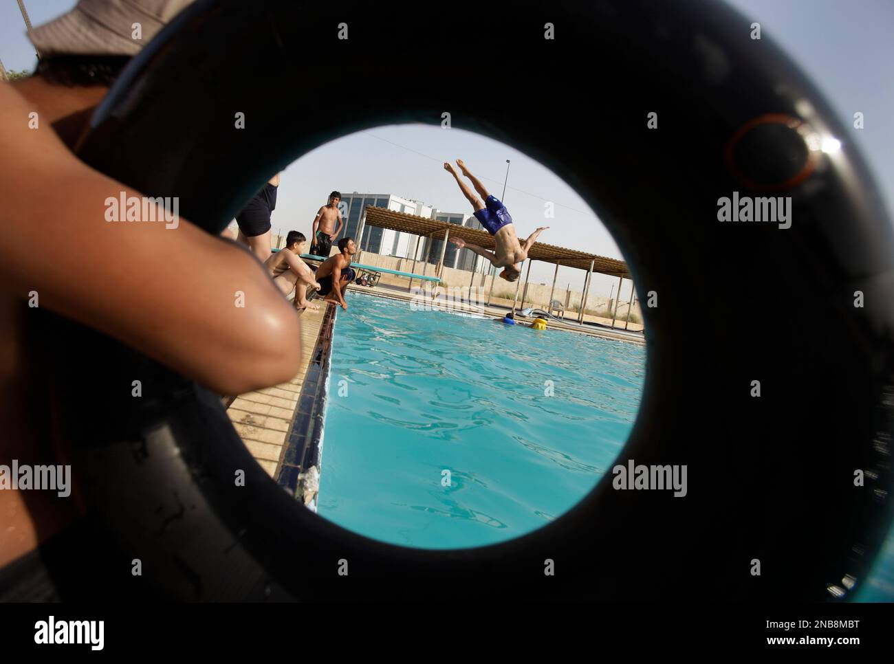 A man dives into a public swimming pool in Baghdad, Iraq, Saturday ...