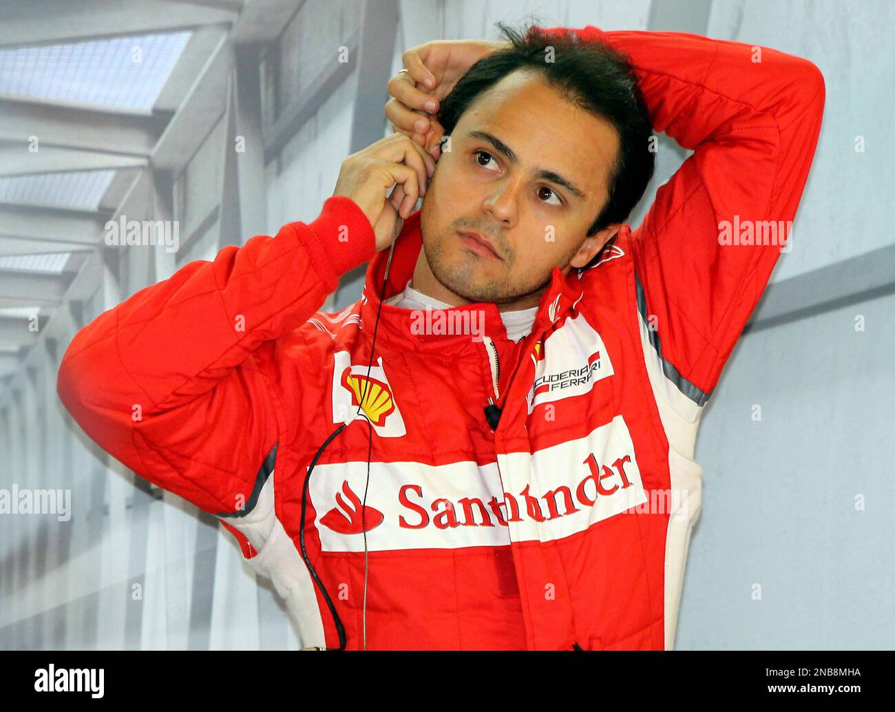 Ferrari driver Felipe Massa, of Brazil, adjusts a earphone at pits ...