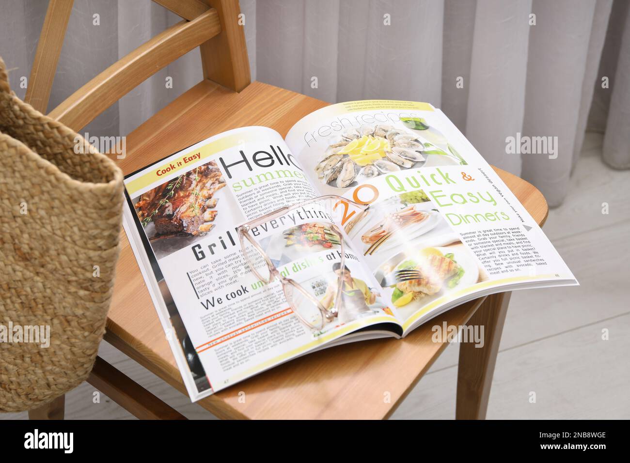 Open healthy food magazine and wicker bag on wooden chair indoors Stock ...