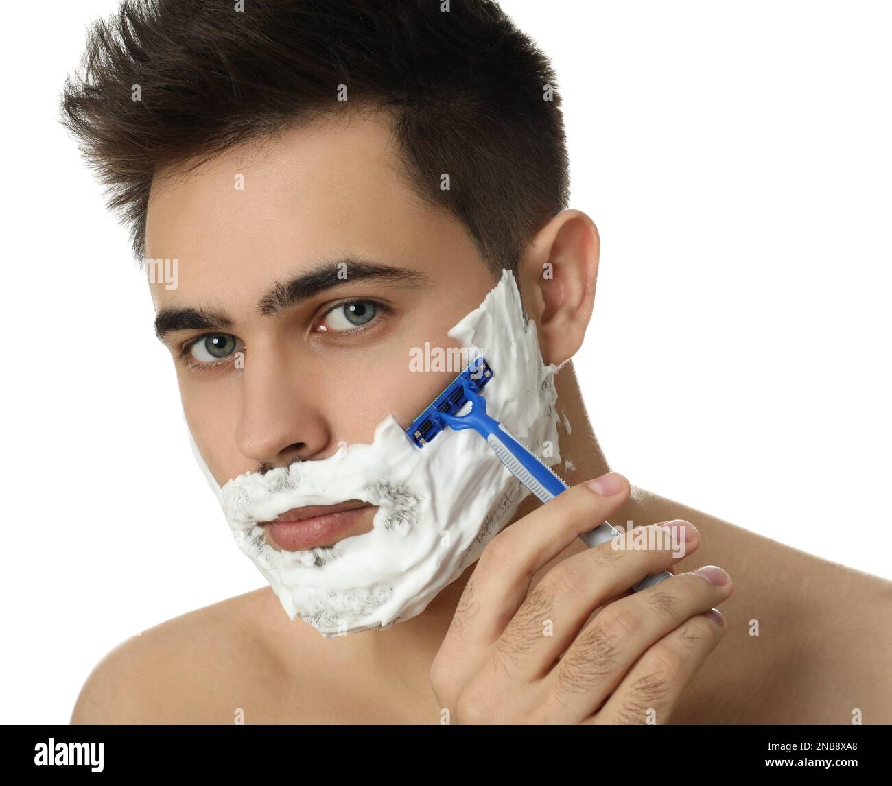 Handsome young man shaving with razor on white background Stock Photo ...