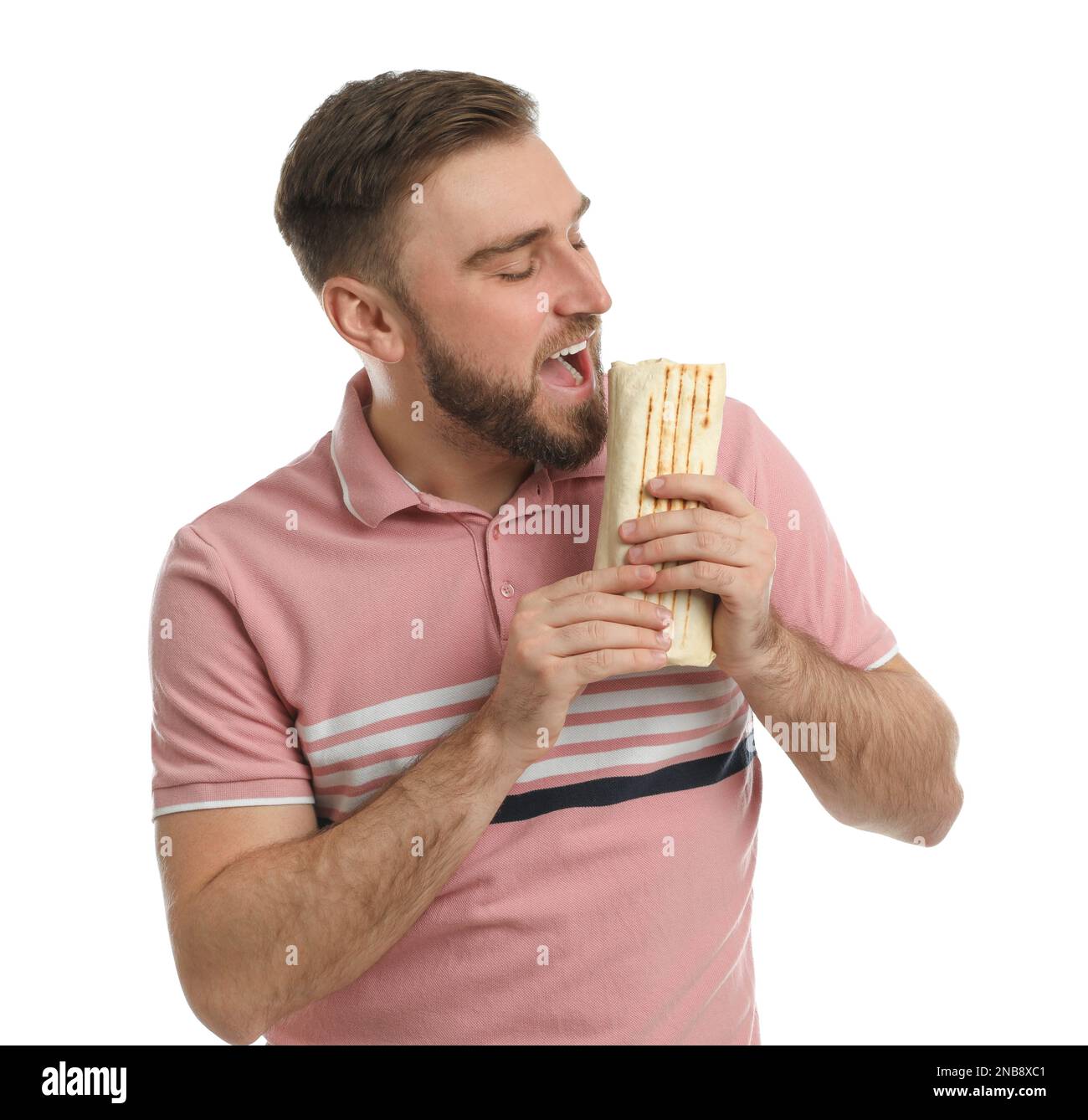 Young man eating delicious shawarma on white background Stock Photo - Alamy
