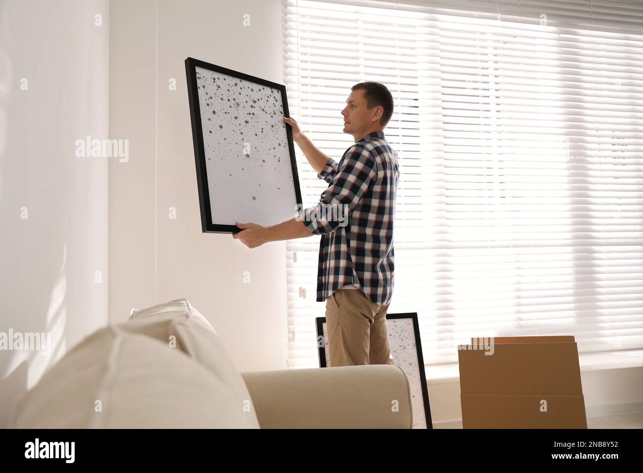 Man holding picture near white wall in room. Interior design Stock ...