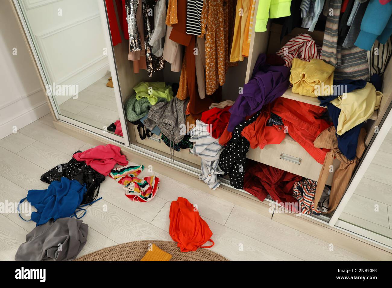 Messy wardrobe with different clothes indoors. Fast fashion concept ...