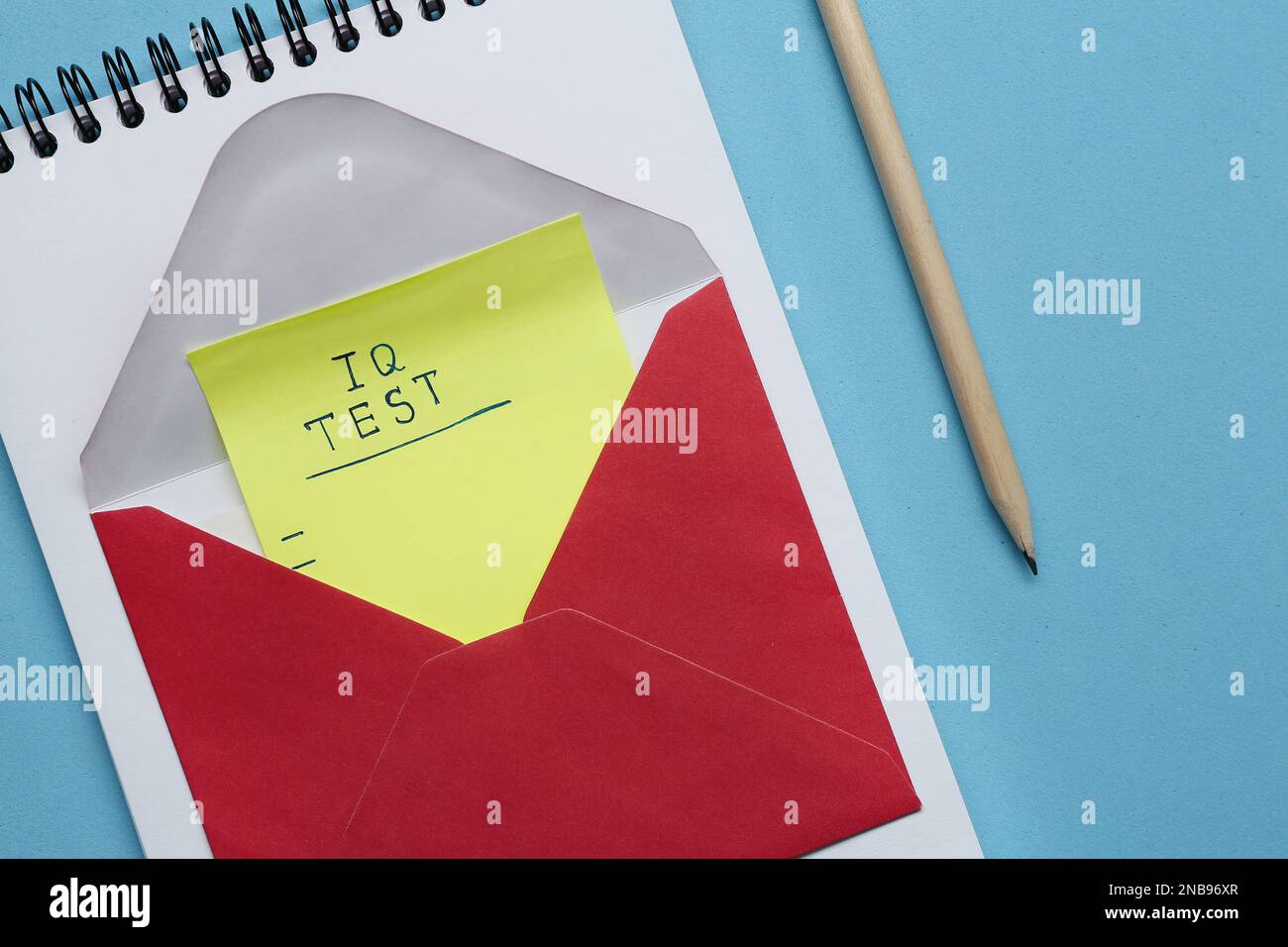 Note with text IQ Test in envelope, notepad and pencil on light blue ...