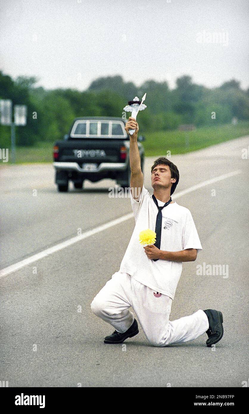 James Michael Lesak, 20, of Houston, holds a cross and an artificial ...