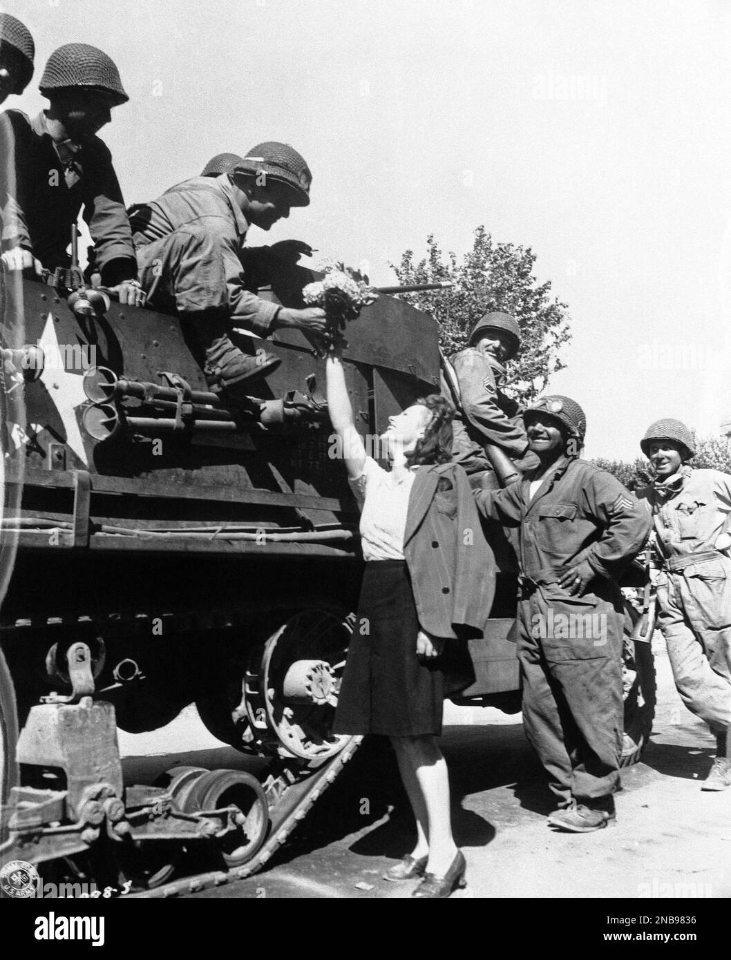 A French women presents flowers to members of an American tank crew in ...
