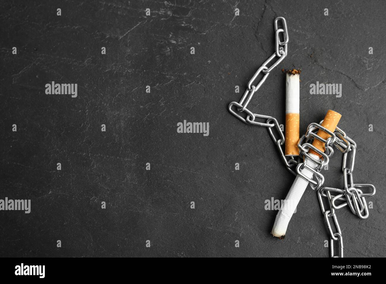 Cigarette stubs and chain on black table, flat lay with space for text ...