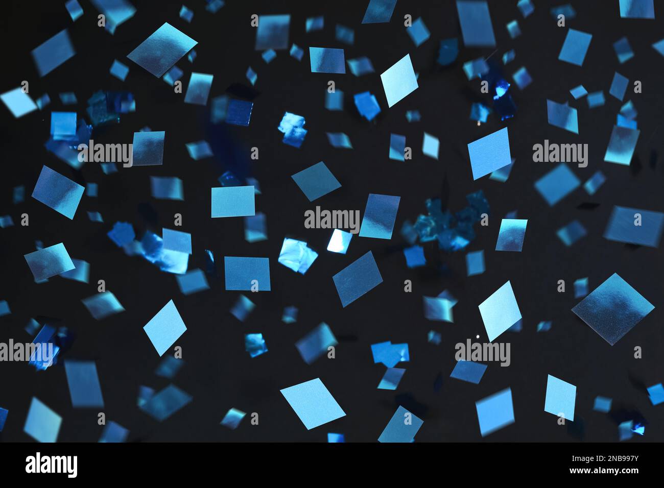 Shiny blue confetti falling down on black background Stock Photo - Alamy