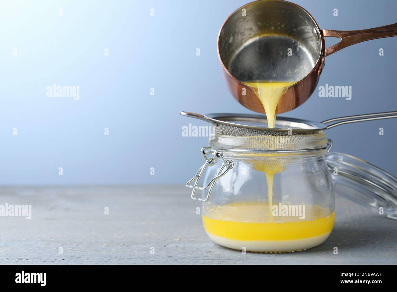 Pouring clarified butter into jar on grey table. Space for text Stock ...