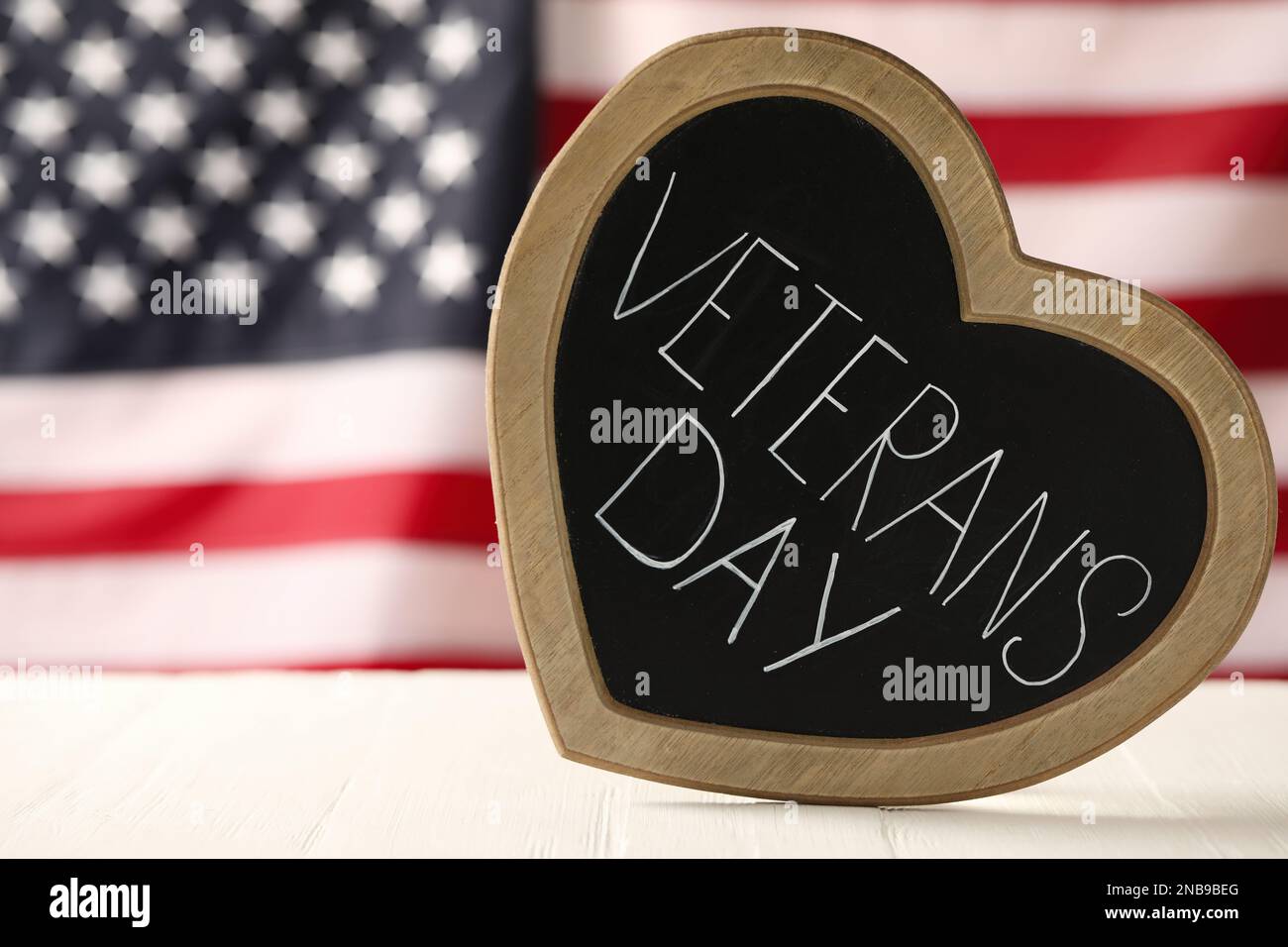 Heart shaped blackboard with phrase Veterans Day on white wooden table ...