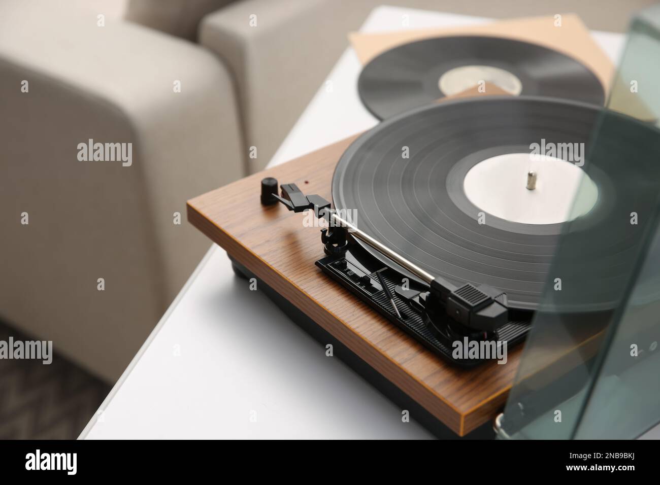 Stylish turntable with vinyl record on white chest of drawers indoors ...