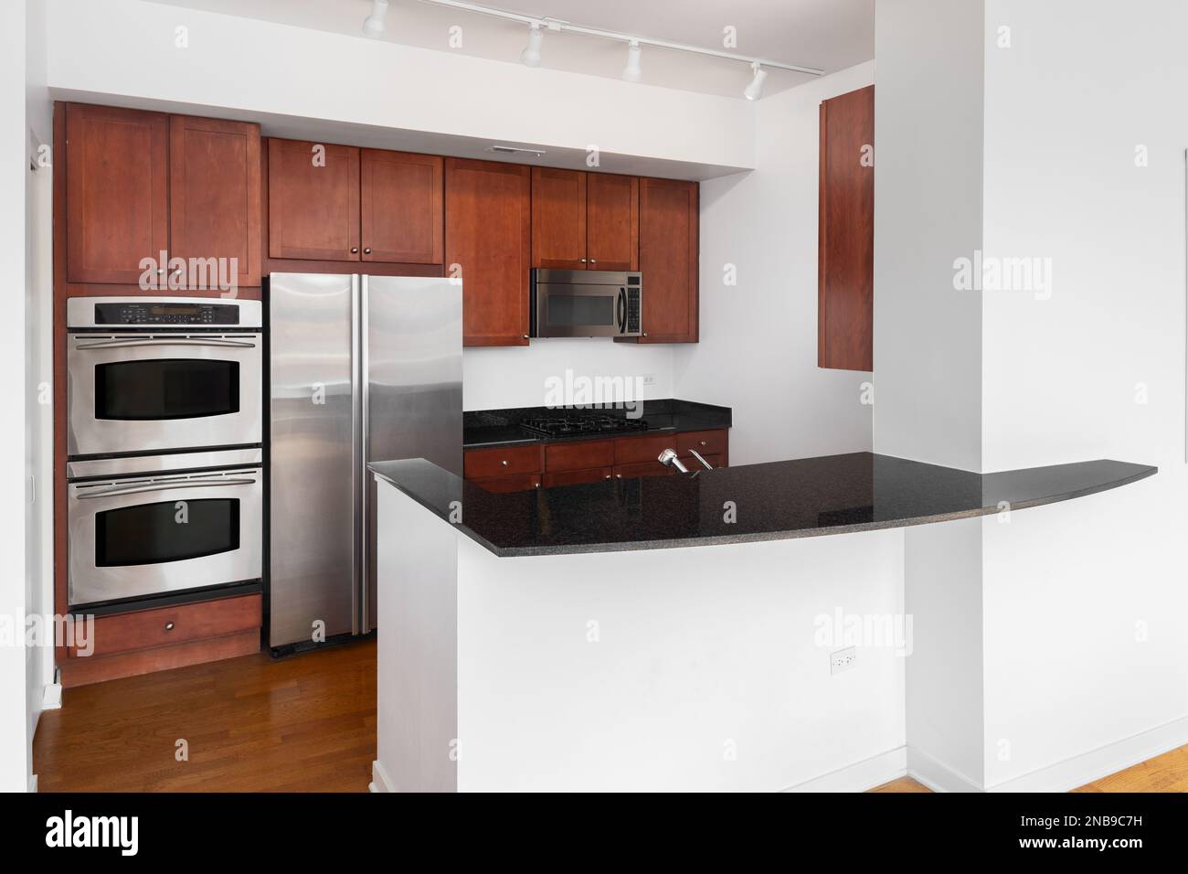 A small kitchen with cherry wood cabinets, stainless steel appliances ...