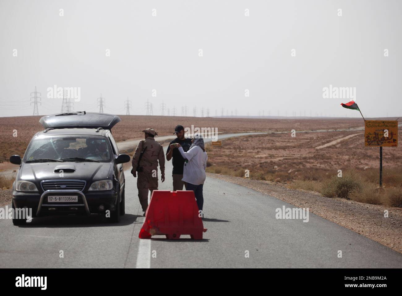Rebel fighters check a car at a checkpoint between Tarhouna and Bani ...