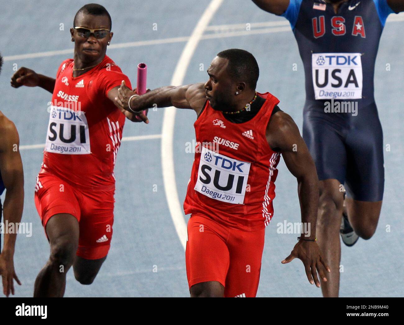 Switzerland's Alex Wilson, center, takes a baton from Reto Schenkel in ...