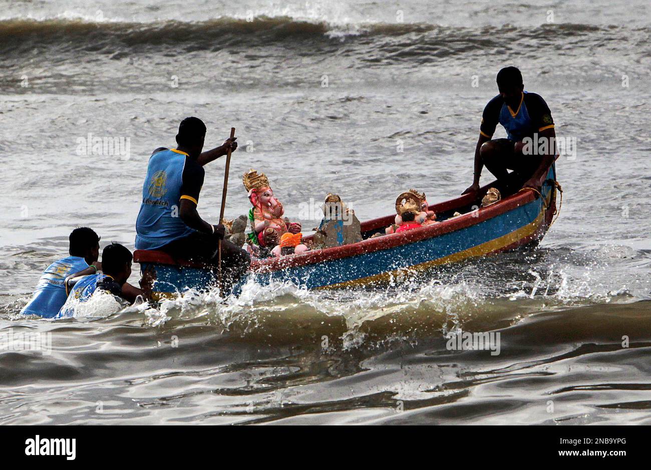 People carry idols of elephant-headed Hindu God Ganesha on a boat for ...