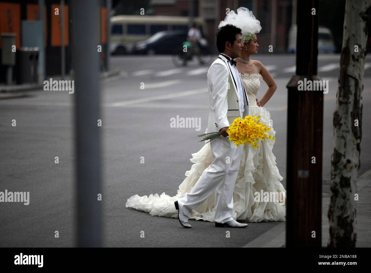 A newly married couple wait for their wedding photo session in a street ...