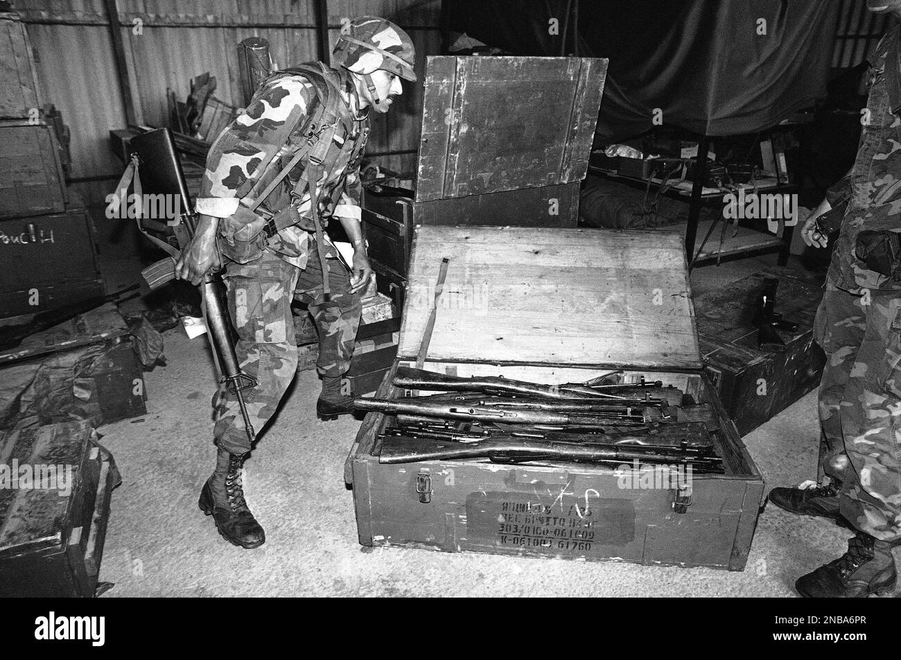 A U.S. soldier looks over a box of assault rifles captured near the ...