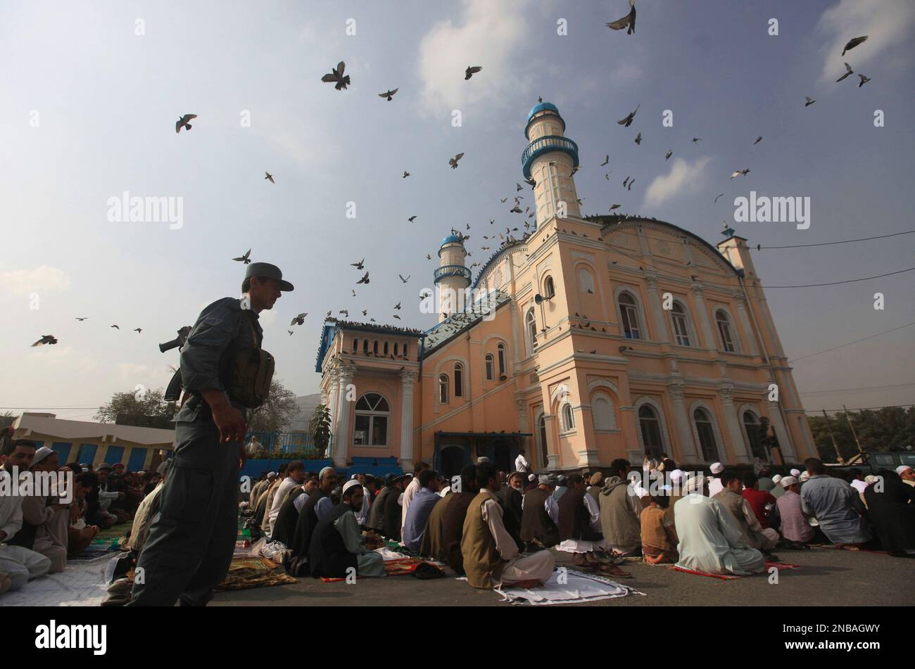 An Afghan police man stands guard as Afghan Muslims offer prayers ...