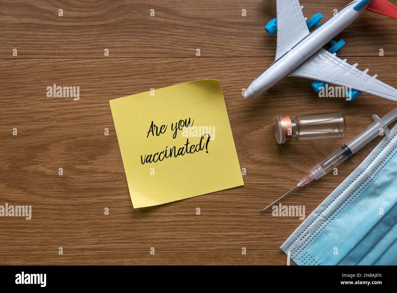 Top view of face mask,syringe, vaccine bottle and plane model with ...
