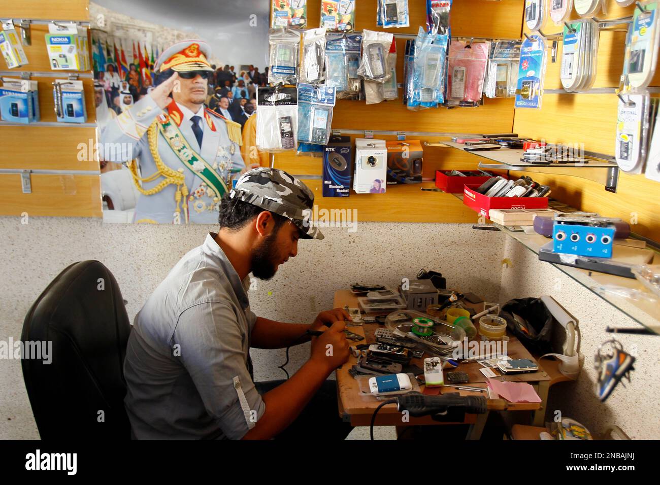 Libyan Jafer Abdel Sadik repairs a telephone in the family shop in a ...