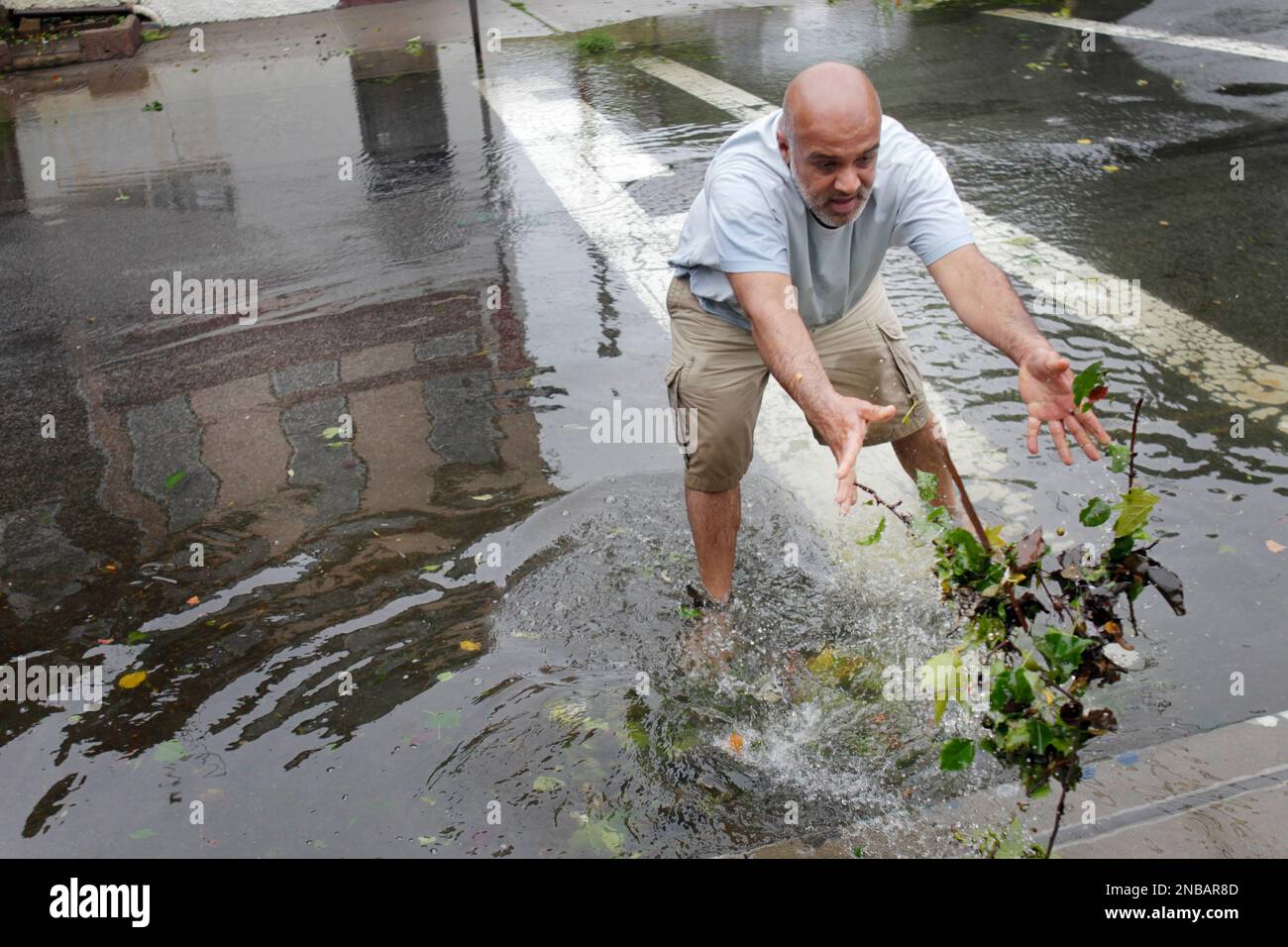 Yeshwant Chitalkar clears a drain in the street of debris with his ...