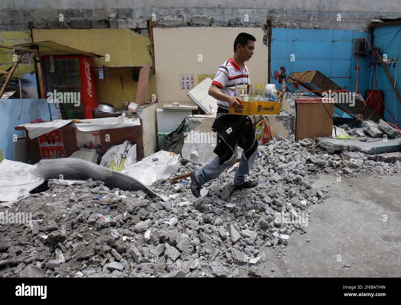 A man salvages bottles along the rubble of a collapsed wall as it was ...