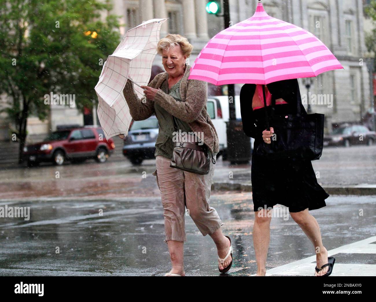 Two women struggle with the initial blast of wind and rain from ...