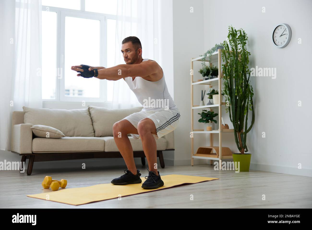 Man sports home training on the floor on a mat with dumbbells ...