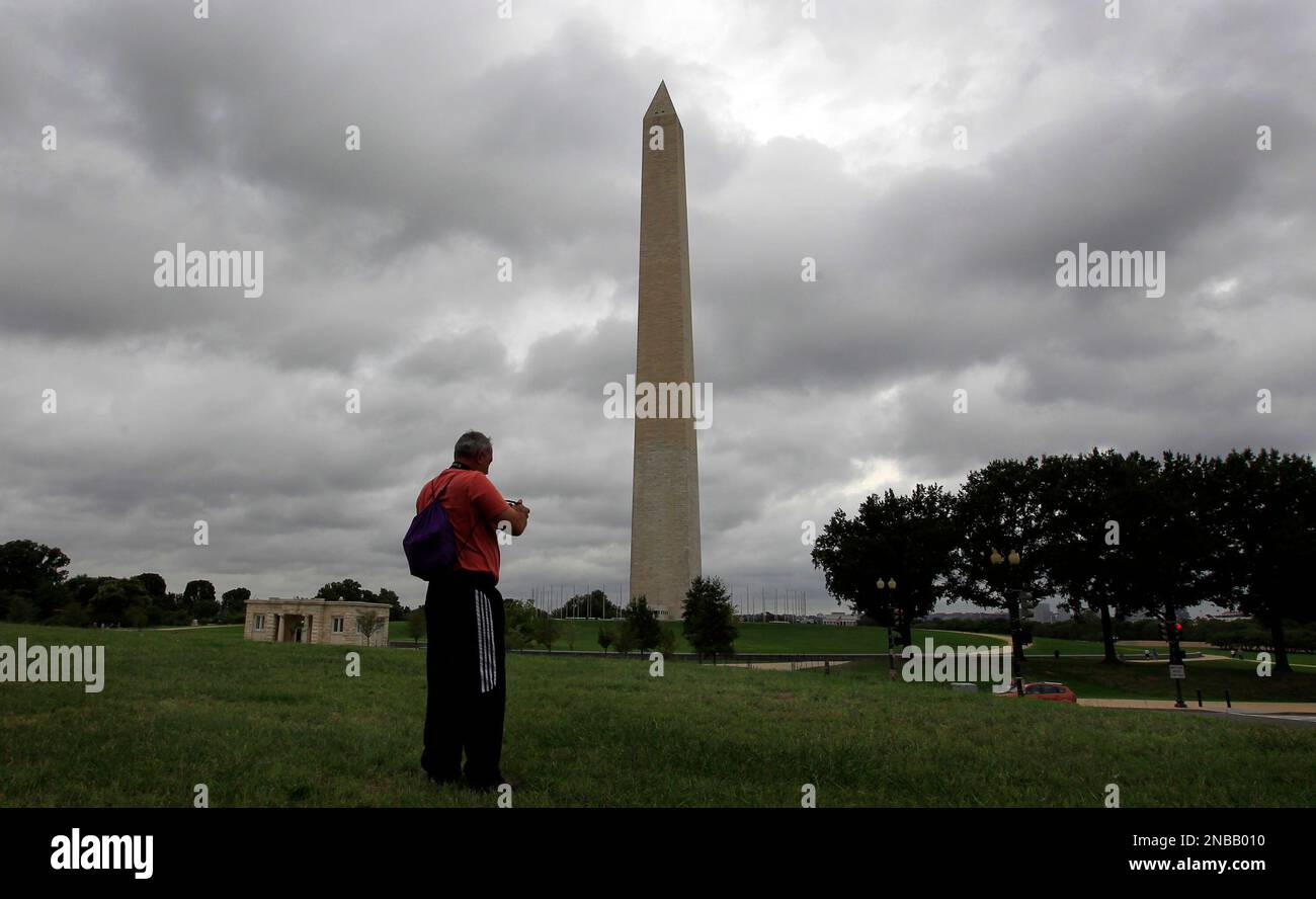 A tourist takes a picture of the recently damaged Washington Monument ...