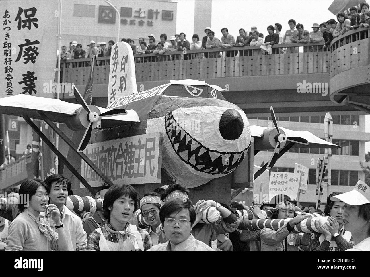 Japanese labor activists carry a model of an aircraft lampooning ...