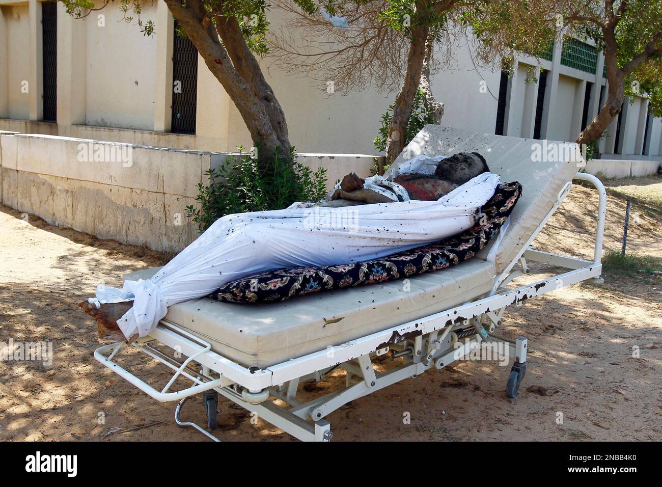 A dead body lies in on a bed outside the hospital in the Abu Salim ...
