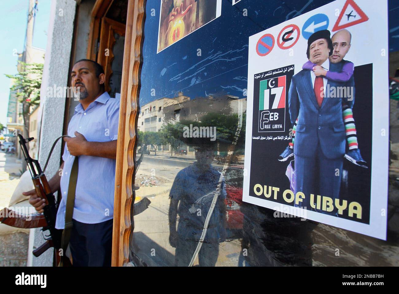 A Libyan rebel stands by a shop window decorated with a portrait of ...