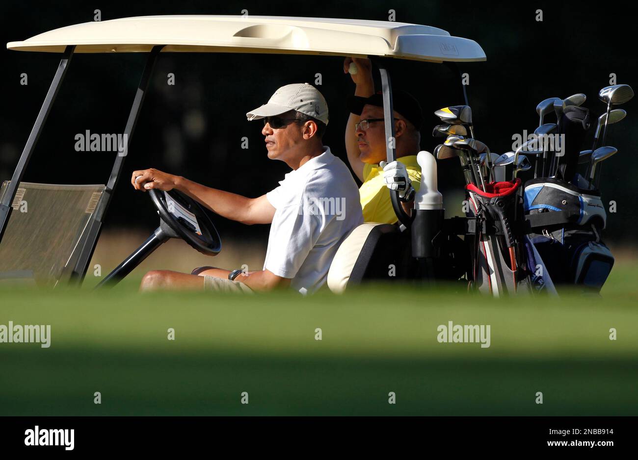 President Barack Obama, left, shares a golf cart with Eric Whitaker ...
